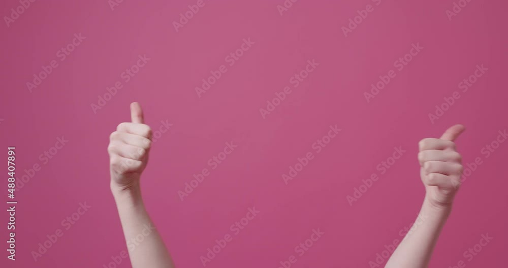 The young woman shows the Like symbol on an isolated pink background ...