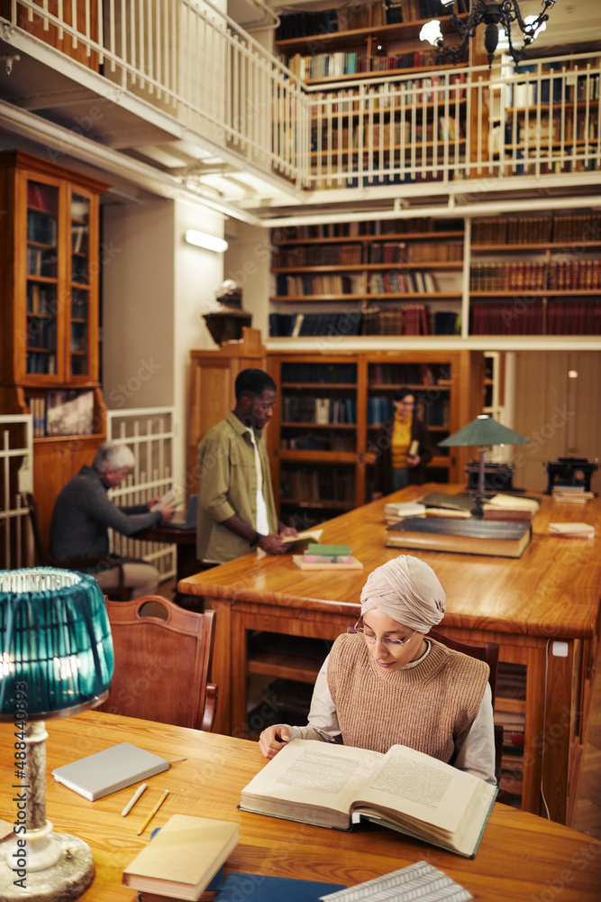 Vertical wide angle shot of classic college library with diverse group ...