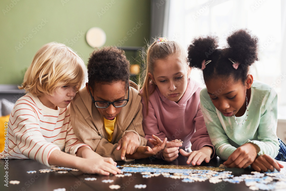 Front view portrait of diverse group of children playing with puzzle ...