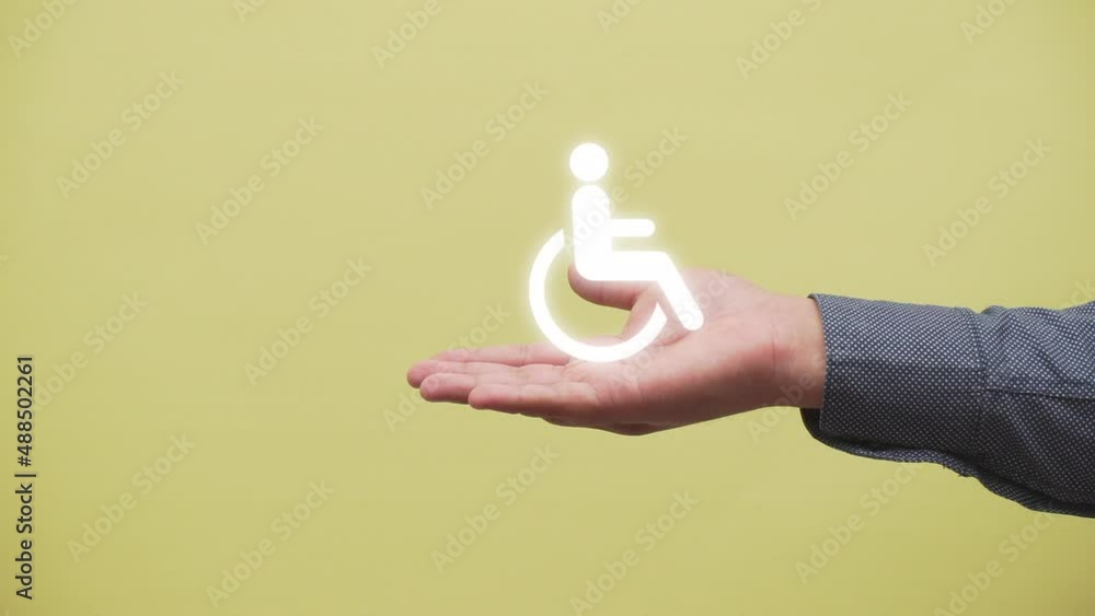 concept of disability. hand shows a symbol of person in wheelchair ...