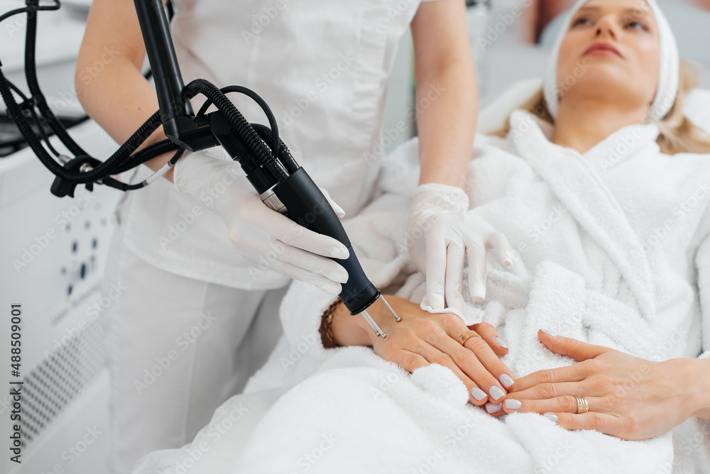 A young girl gets carbon peeling for the skin of her hands in a beauty ...