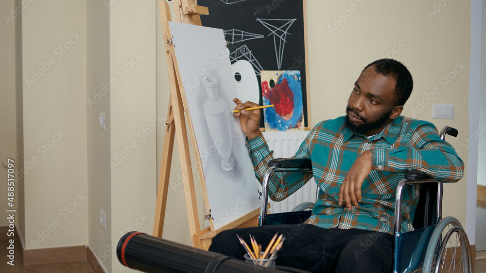 African american man with disability using pencil to draw on canvas ...