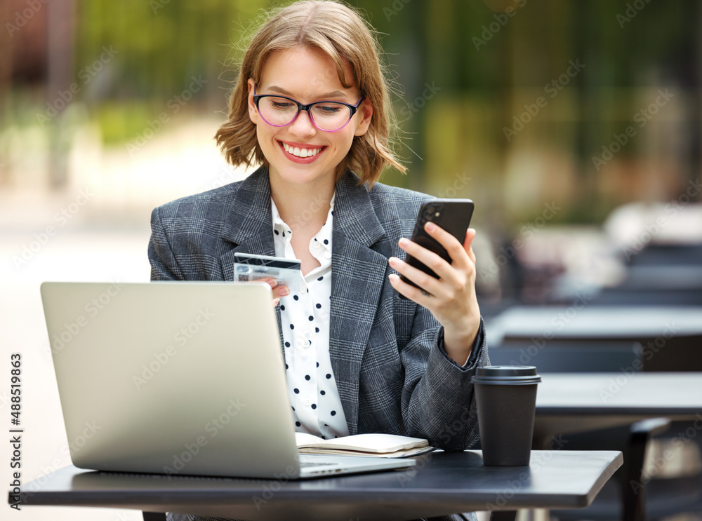 Positive business lady with mobile phone and credit bank card smiling ...