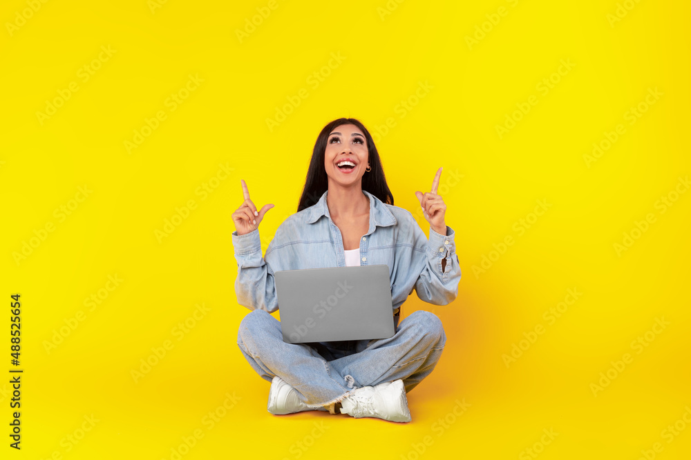 Happy lady using laptop pointing up at studio Stock Photo | Adobe Stock