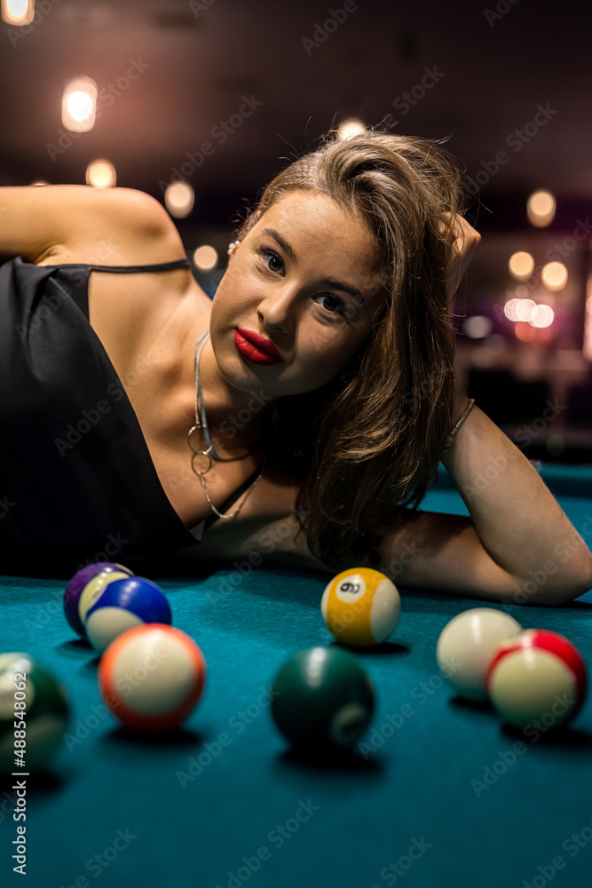 Sexy female pool player wear black dress lying on billiard table Stock ...