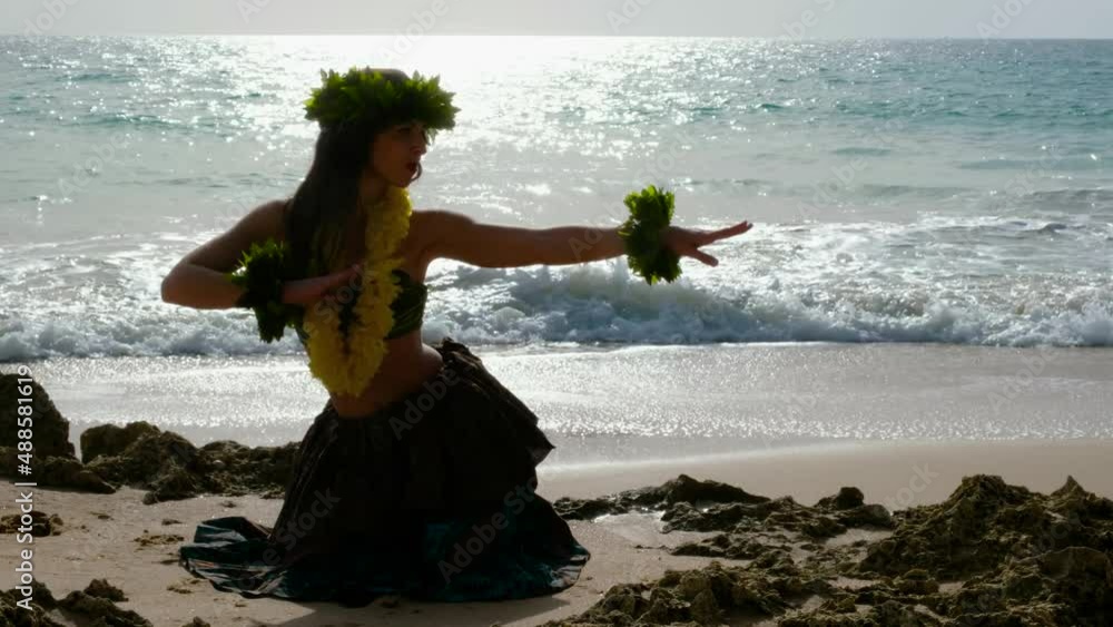 Woman dancing hawaiian hula dance waving her hands on the beach sitting ...