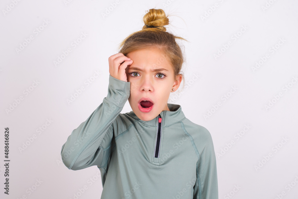 Embarrassed little caucasian kid girl with hair bun wearing technical ...