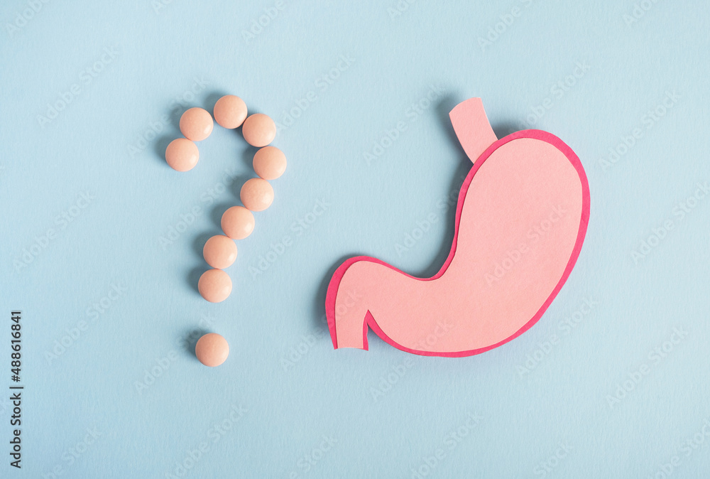 Stomach decorative model with pills in shape question mark on light ...