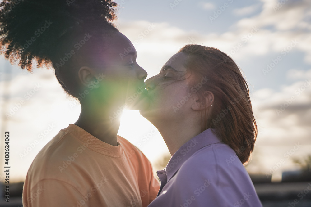 Multiracial Lesbian Couple Kissing Together At Sunset Outdoor Stock