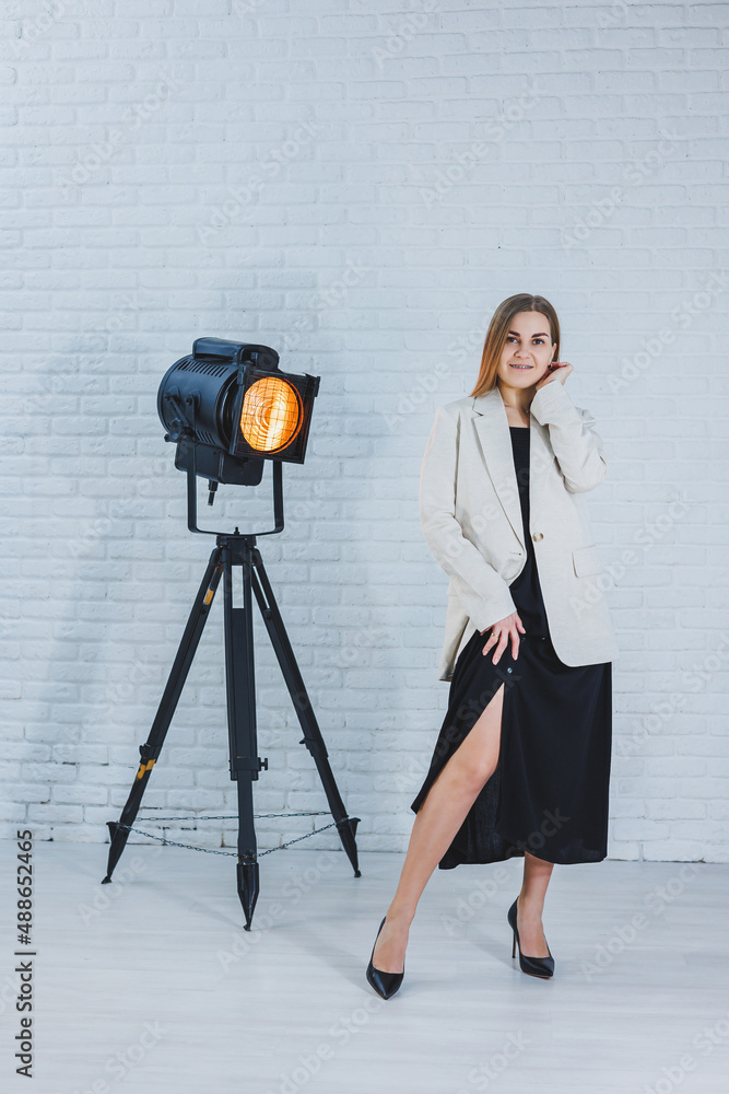 Gorgeous slender brown-haired woman in a black dress and a beige jacket ...