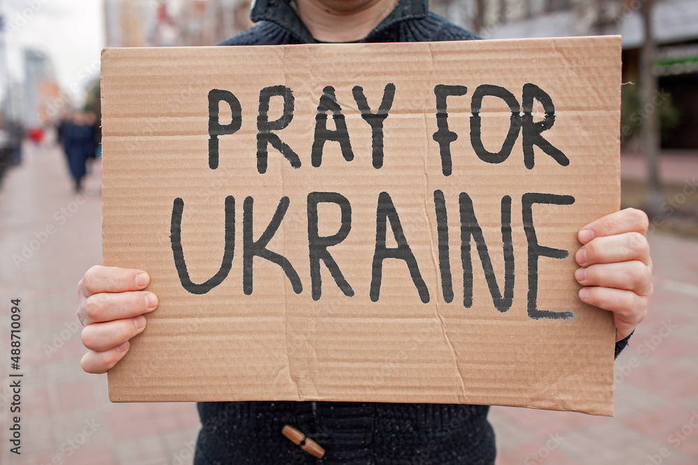Middle aged civil man stands on crowded city street and holds a poster ...