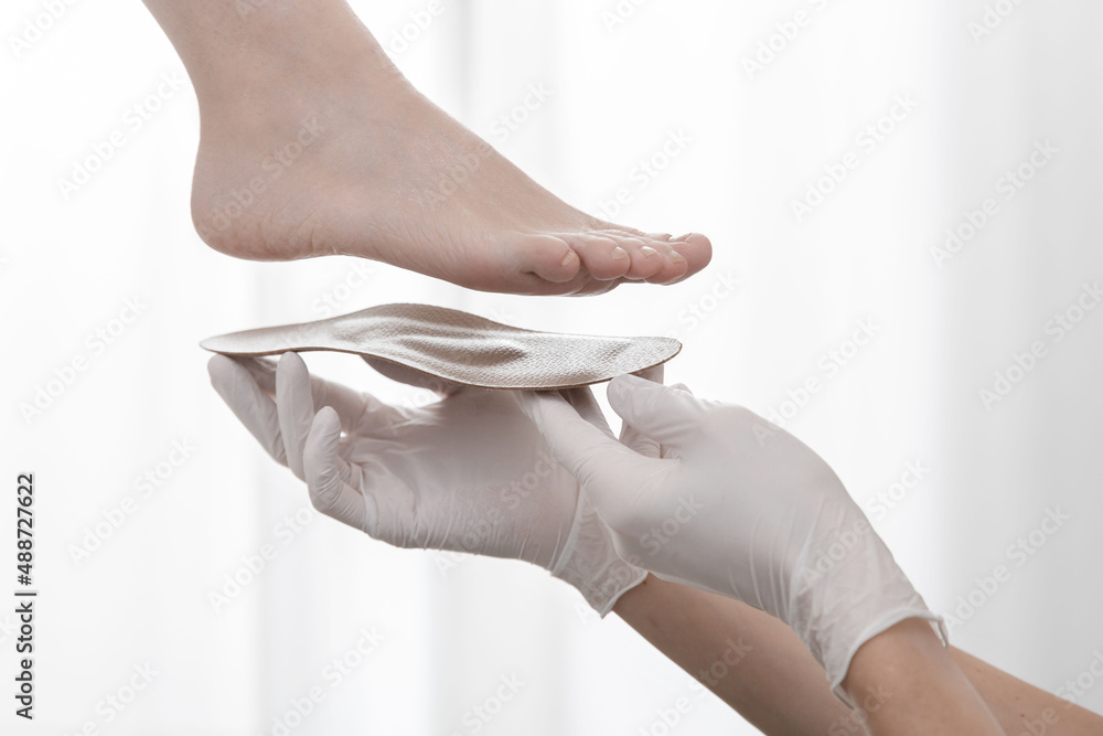 Orthopedic insole on a white background. Hands in rubber gloves hold an ...