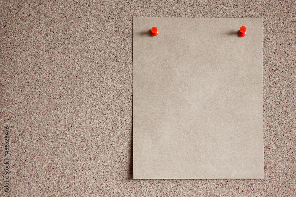 Blank Brown paper note with pin on corkboard. With copy space for ideas ...