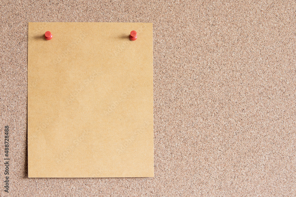 Blank Brown paper note with pin on corkboard. With copy space for ideas ...
