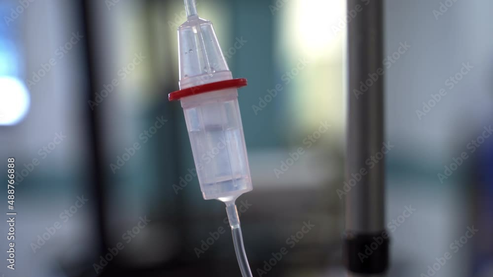 Transparent dropper with medical liquid dribbling down in hospital ward ...