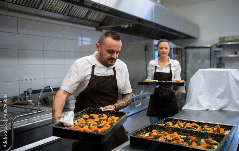 Chef and cook working on their dishes indoors in restaurant kitchen ...