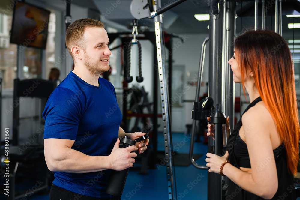 Woman customer talking with sport trainer coach at modern gym hall ...
