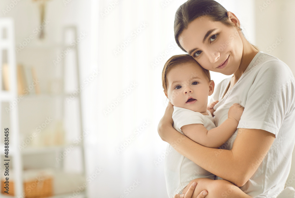 White text copyspace background with a tender portrait of a happy beautiful young mom holding ...