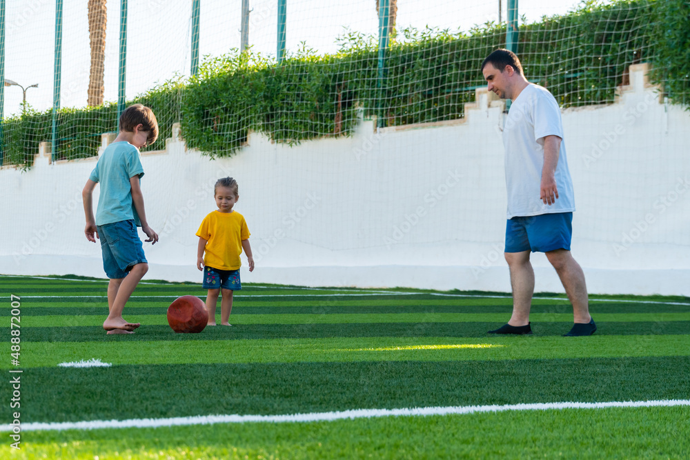 Full body man playing football with children on green lawn. Father's ...
