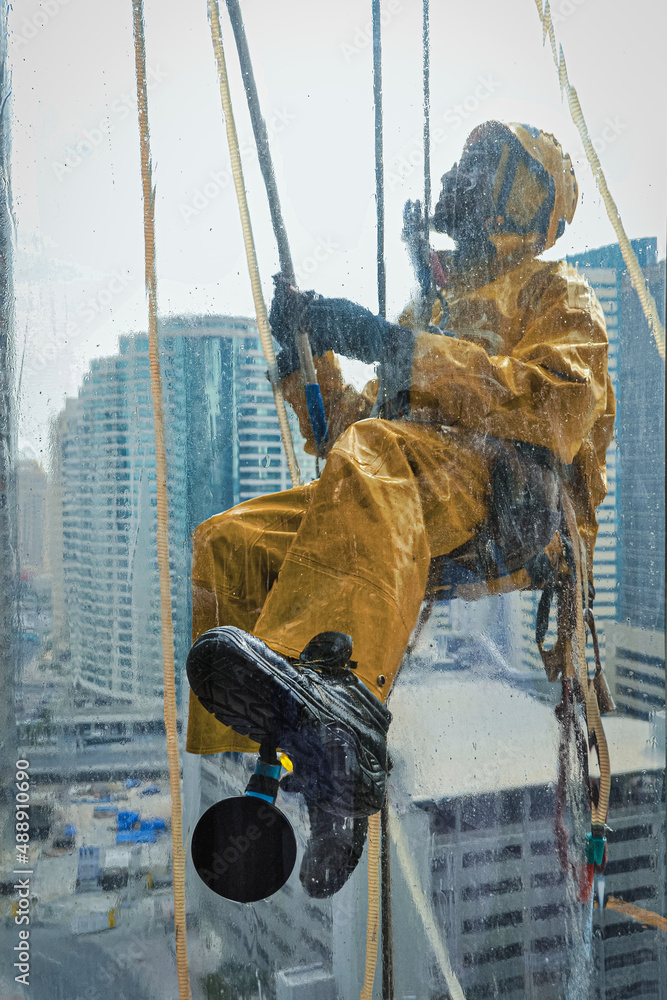 Skyscraper window cleaner hanging from a harness in Doha, Qatar. View ...