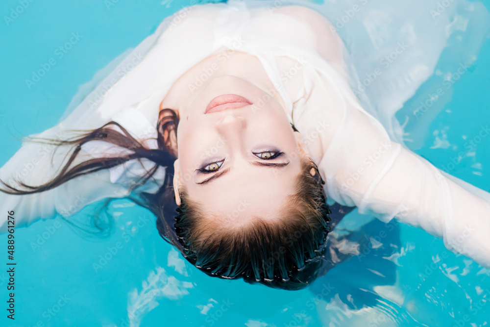 Top view, portrait of a young, beautiful woman floating in the pool ...