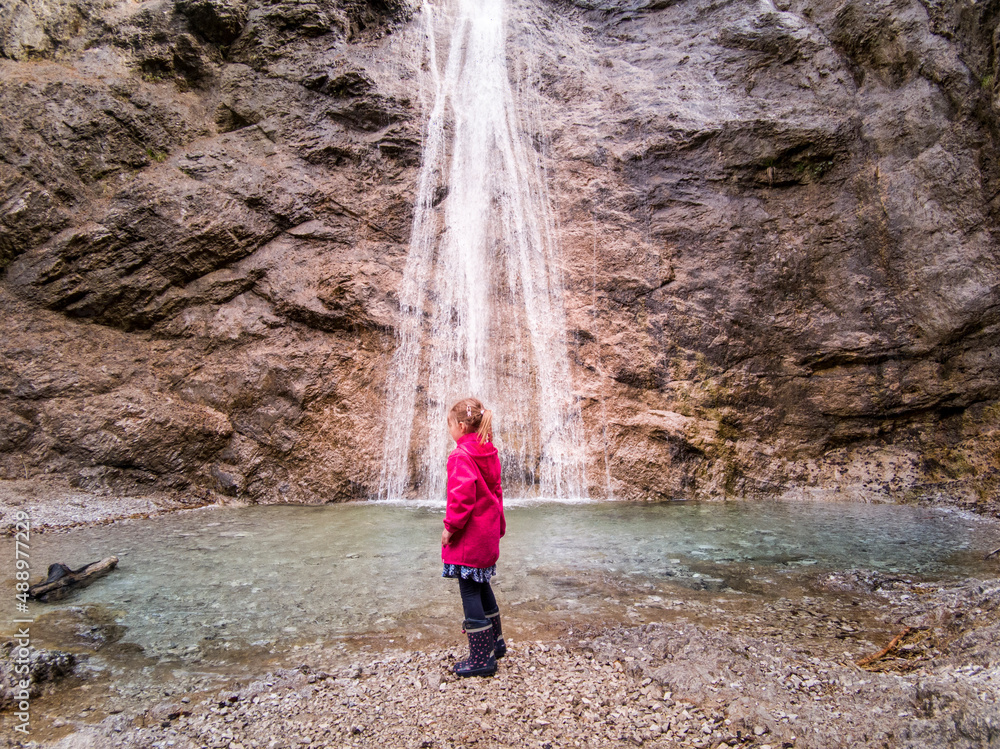 Kind steht vor Wasserfall mit klarem Wasser in Naturschutzgebiet ...