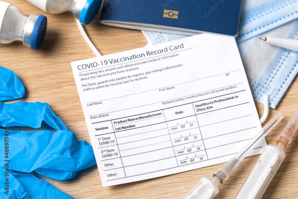 Top view of vaccination record card, syringes, and two vials of the ...