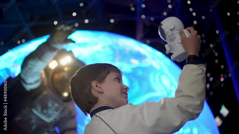 Happy cute boy dreaming flying toy astronaut rocket at background ...