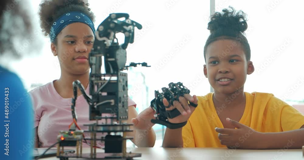 African black kids is playing with robotic arm in a school. Group ...
