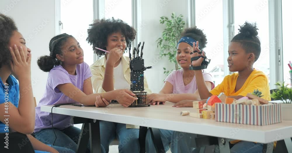 African black kids is playing with robotic arm in a school. Group ...
