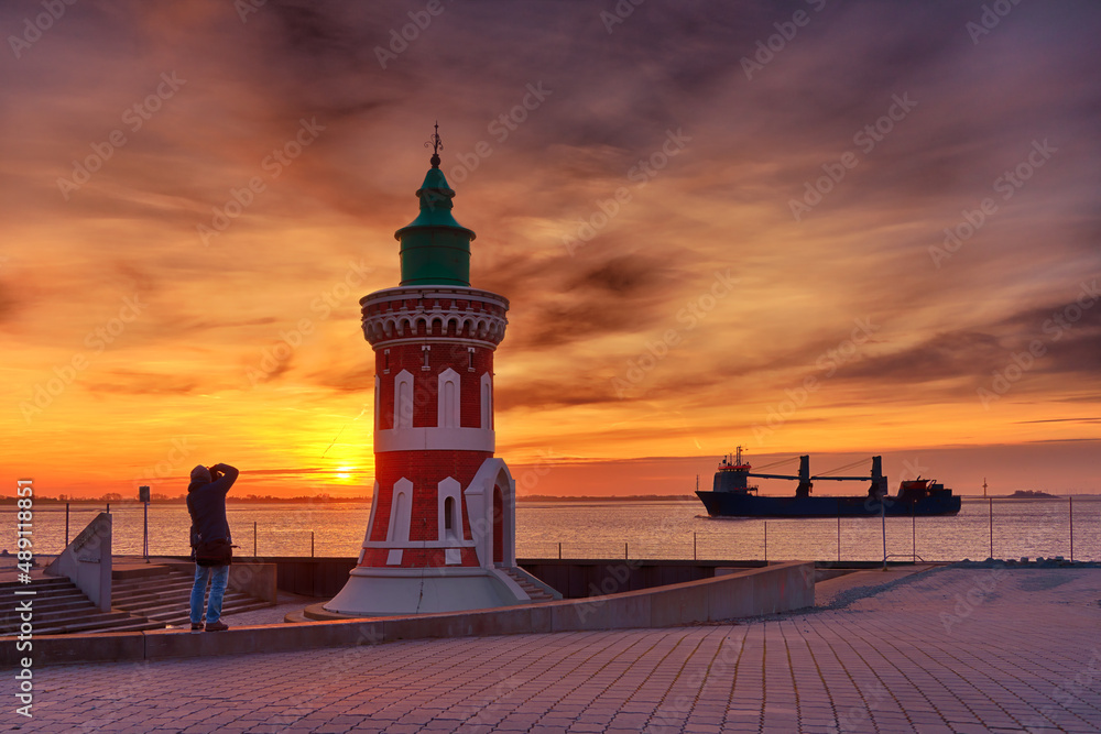 person takes a photo of a lighthouse in Bremerhaven (Germany) in front ...