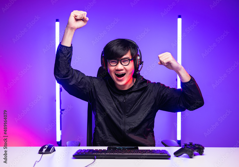 Excited and shocked face of Asian gamer with headphone playing computer ...