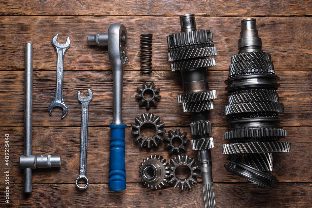 Disassembled parts of car gearbox and work tools wrenches on the wooden ...