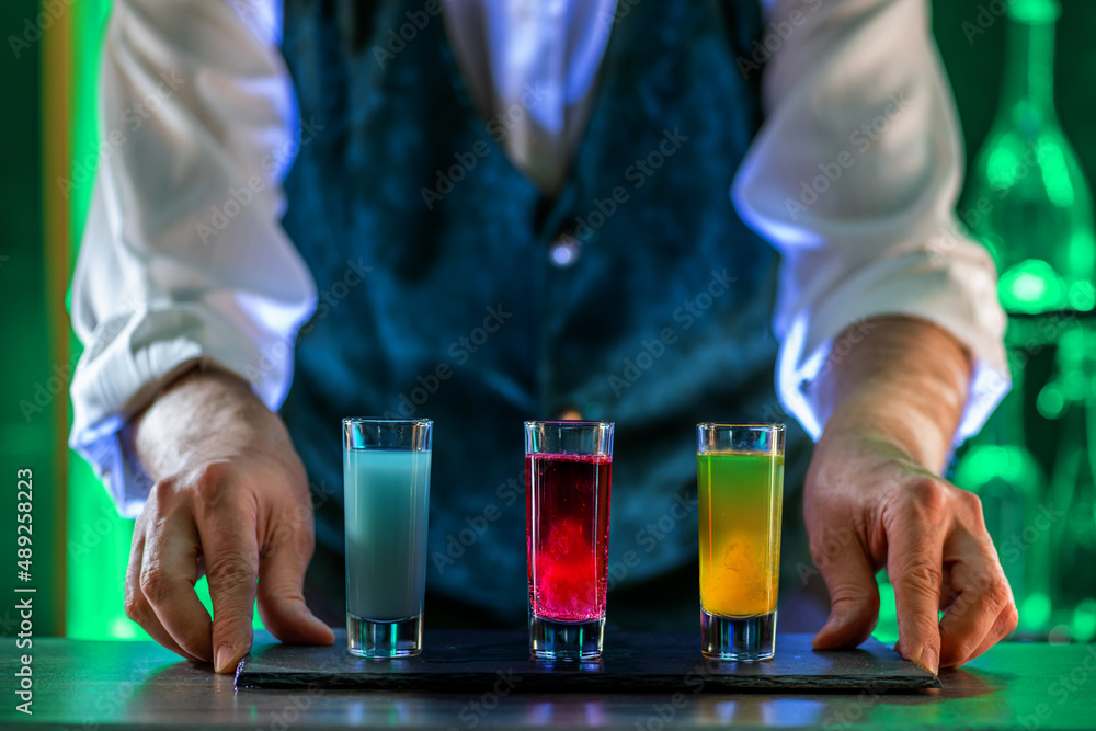 Bartender's hands serving cocktails burning Shots and Shooters on bar ...