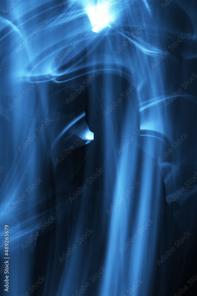 Abstract human silhouette in light trails of light painting with blue ...