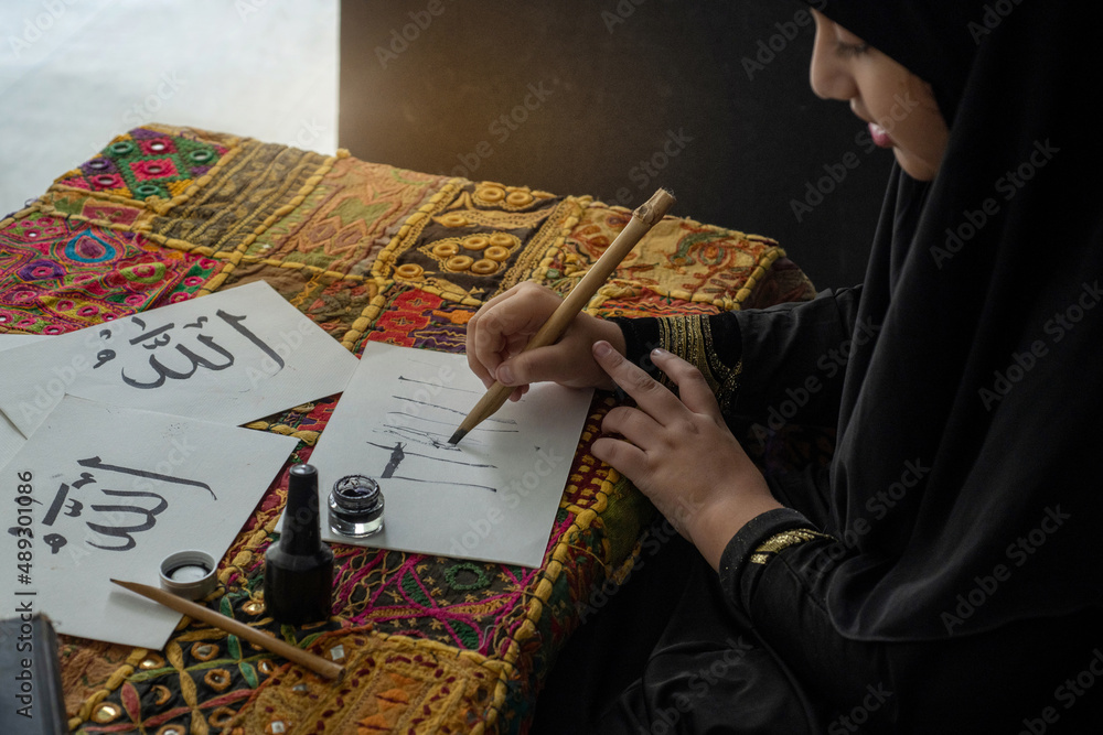Foto de Little Muslim girl wearing black hijab practicing writing ...