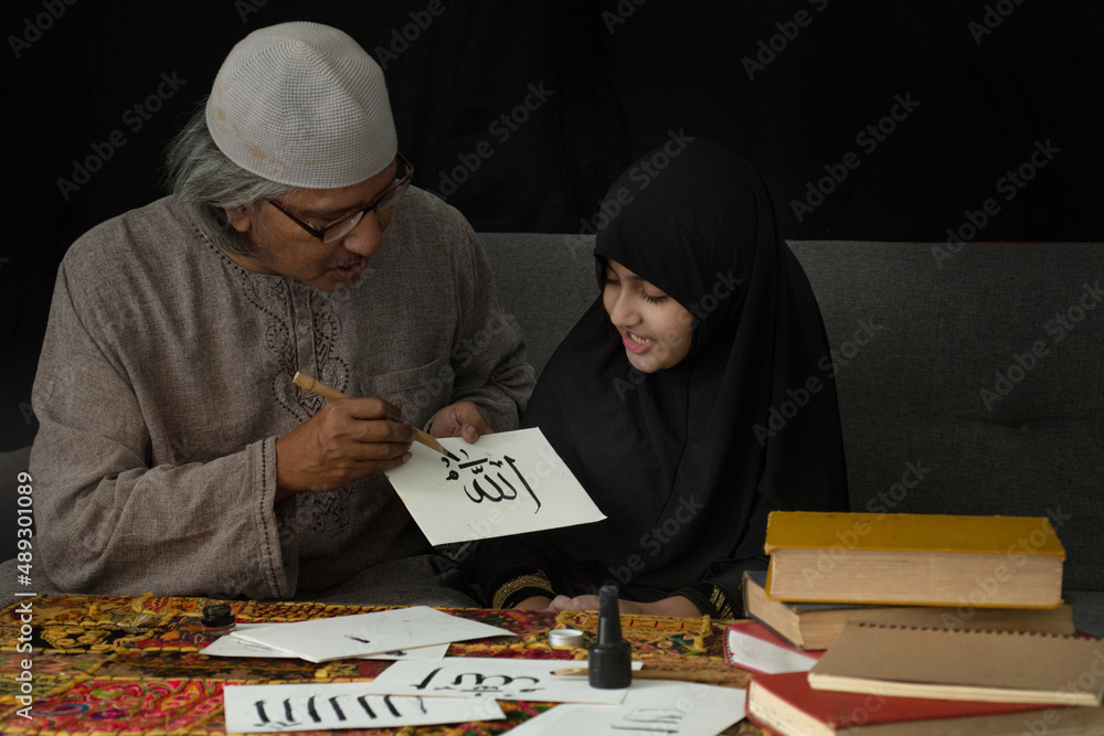 Little Muslim girl wearing hijab learn to write Arabic alphabet with ...