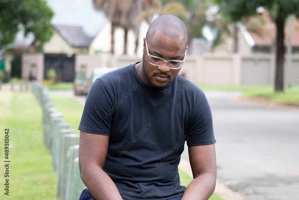 Black African Man sitting on a log looking down Stock Photo | Adobe Stock