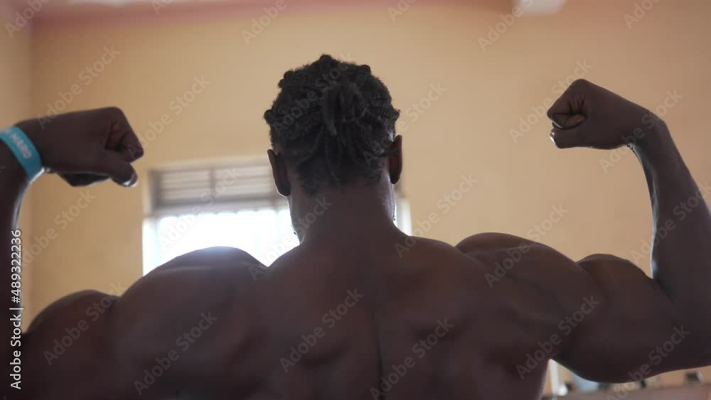 Black African bodybuilder posing in an old school gym in Africa. Back ...