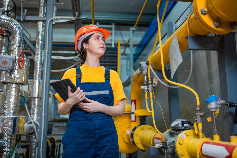 Production inspection. A young engineer in a uniform and a protective ...