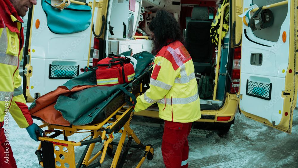 Female Paramedic Pushing a Stretcher INto The Ambulance With Her Male ...