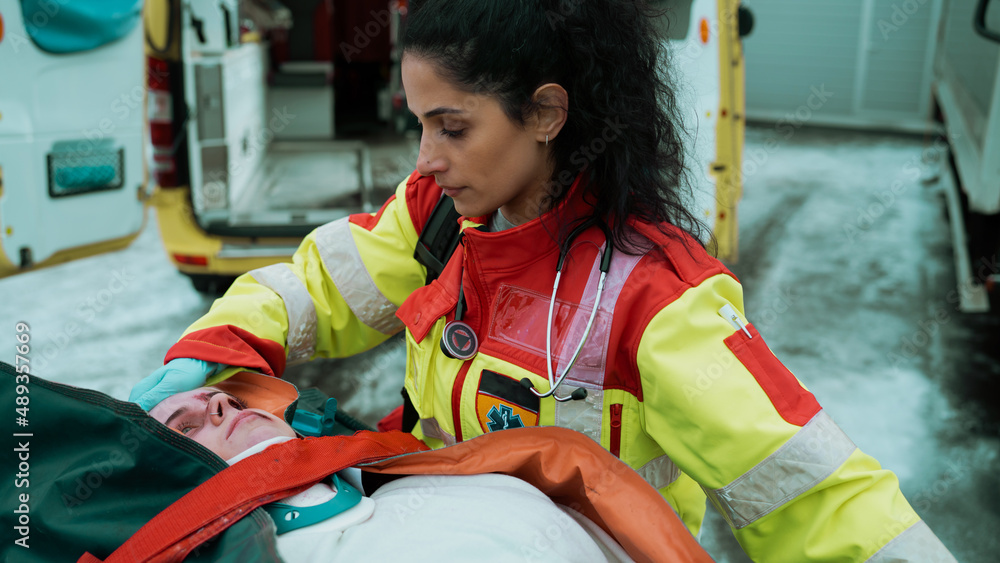 Young Female Ethnic Paramedic Pushing a Stretcher Into The Ambulance ...