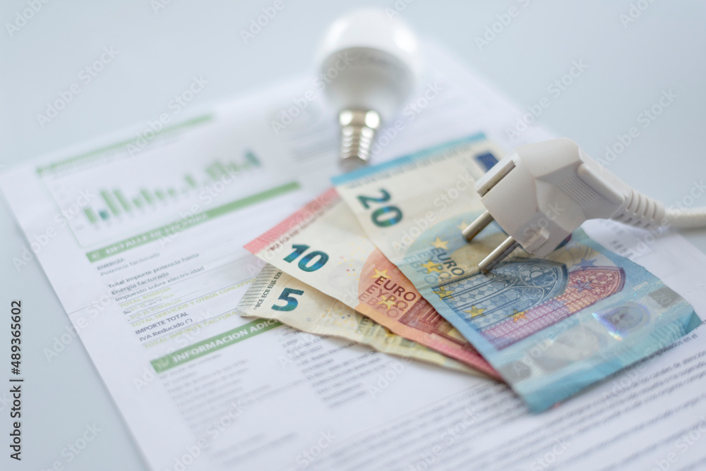 a white electric cap, a light bulb and euro banknotes on an electricity ...