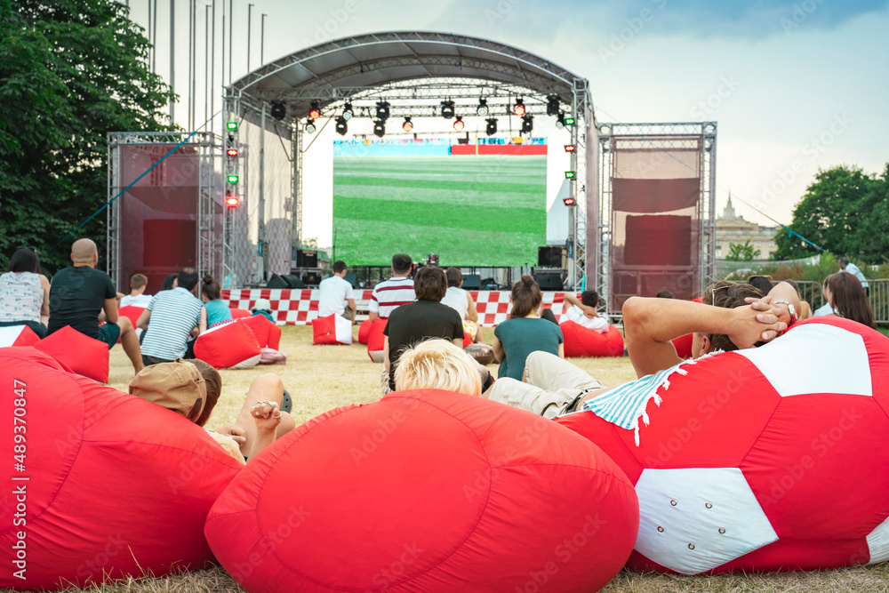 Outdoor event group of people watching soccer game on outdoor screen in ...