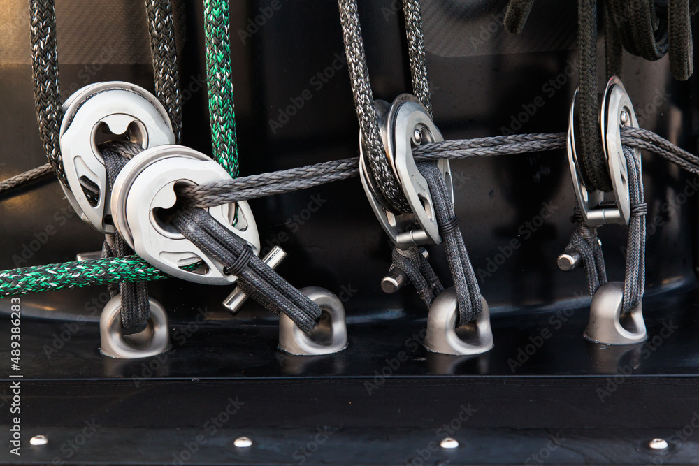 Part of the mast and hull of a sailing yacht, with multi-colored ropes ...