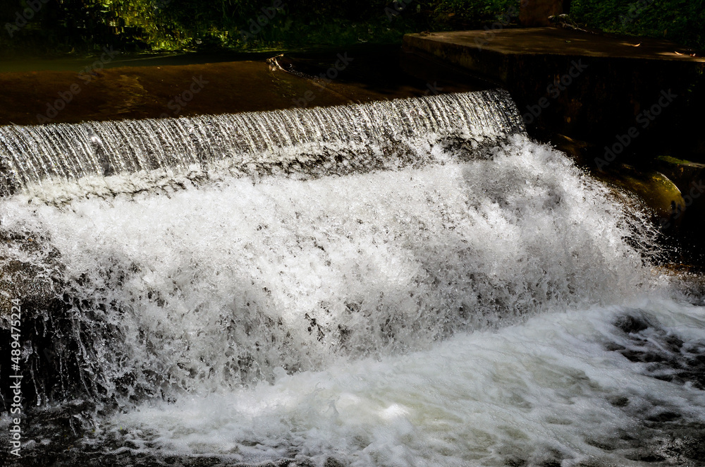 Natural stream of water. A small waterfall caused by man-made dam ...