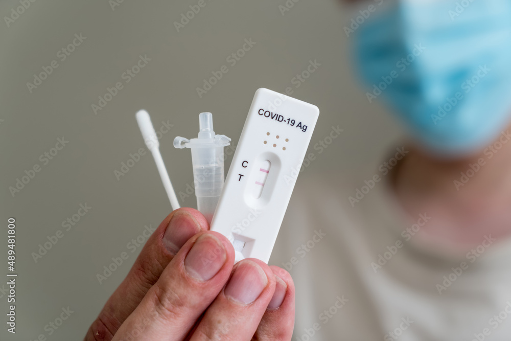 Man wearing face mask holding Covid-19 rapid antigen test kit and ...
