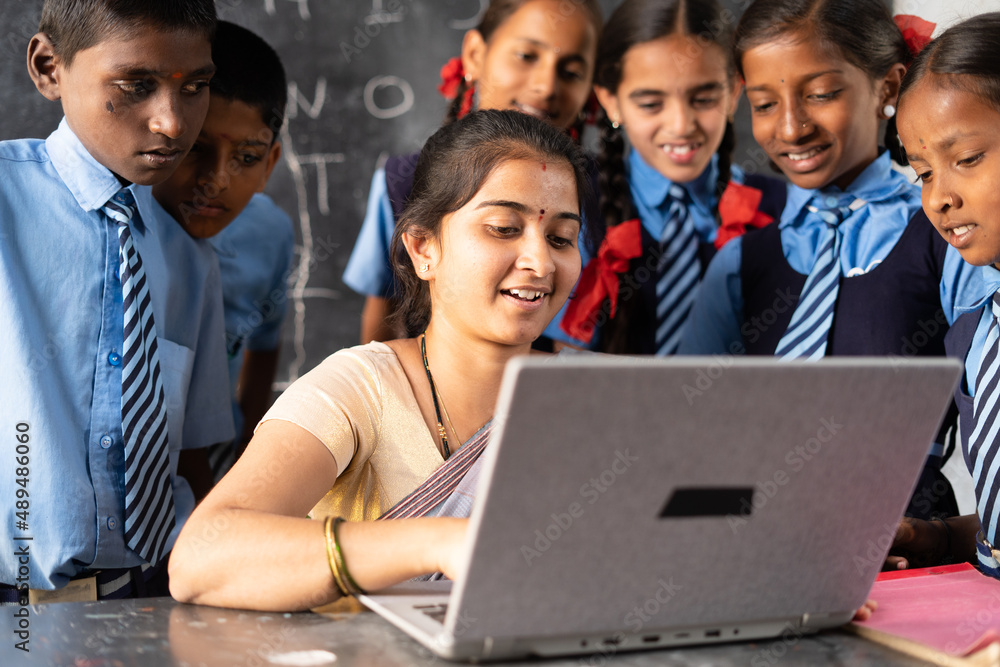 Young indian teacher teaching on laptop with school uniform students at ...
