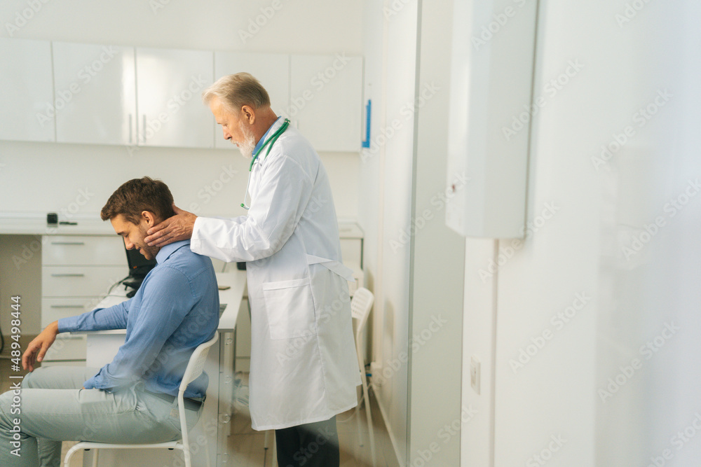 Side view of mature adult male manual therapist turning and bending ...