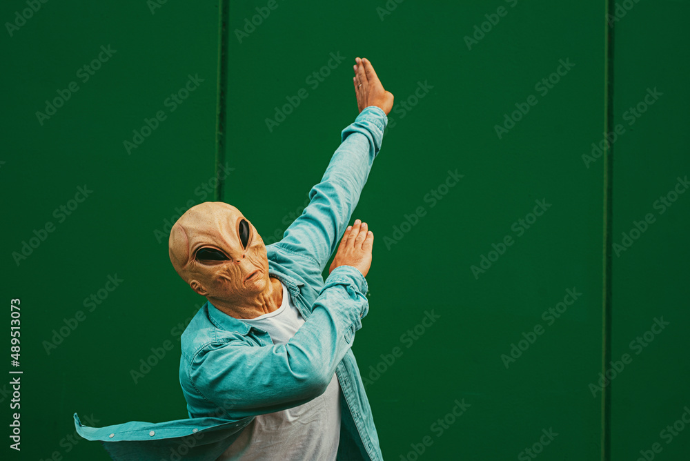 Alien doing dab posture and gesture against a green wall background ...